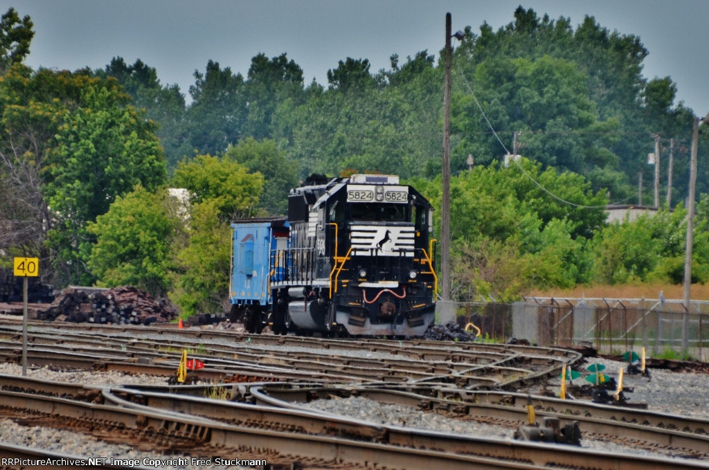 NS 5824 and a former Conrail caboose are off duty in the yard.